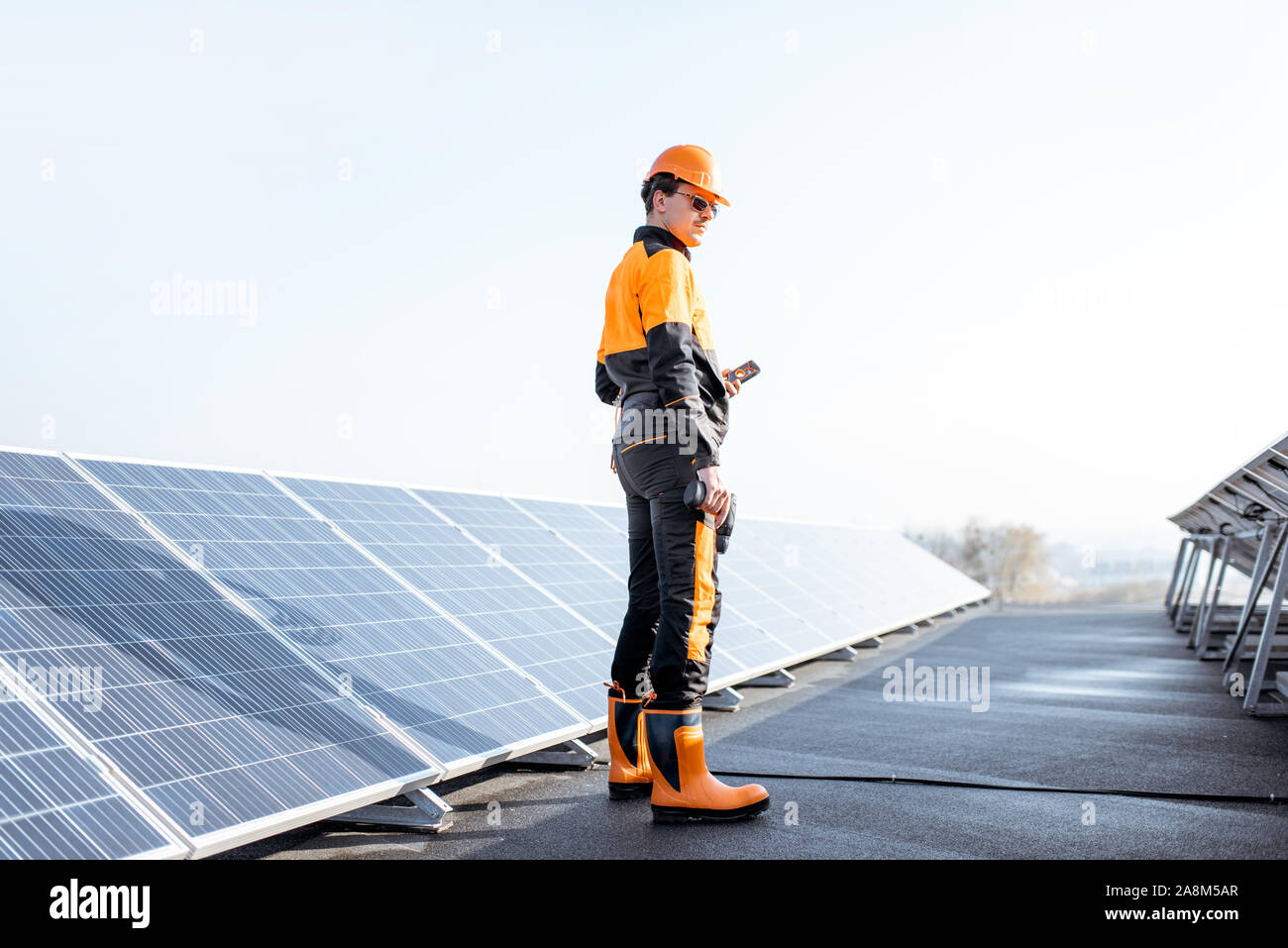 Well-equipped worker in protective orange clothing examining solar ...