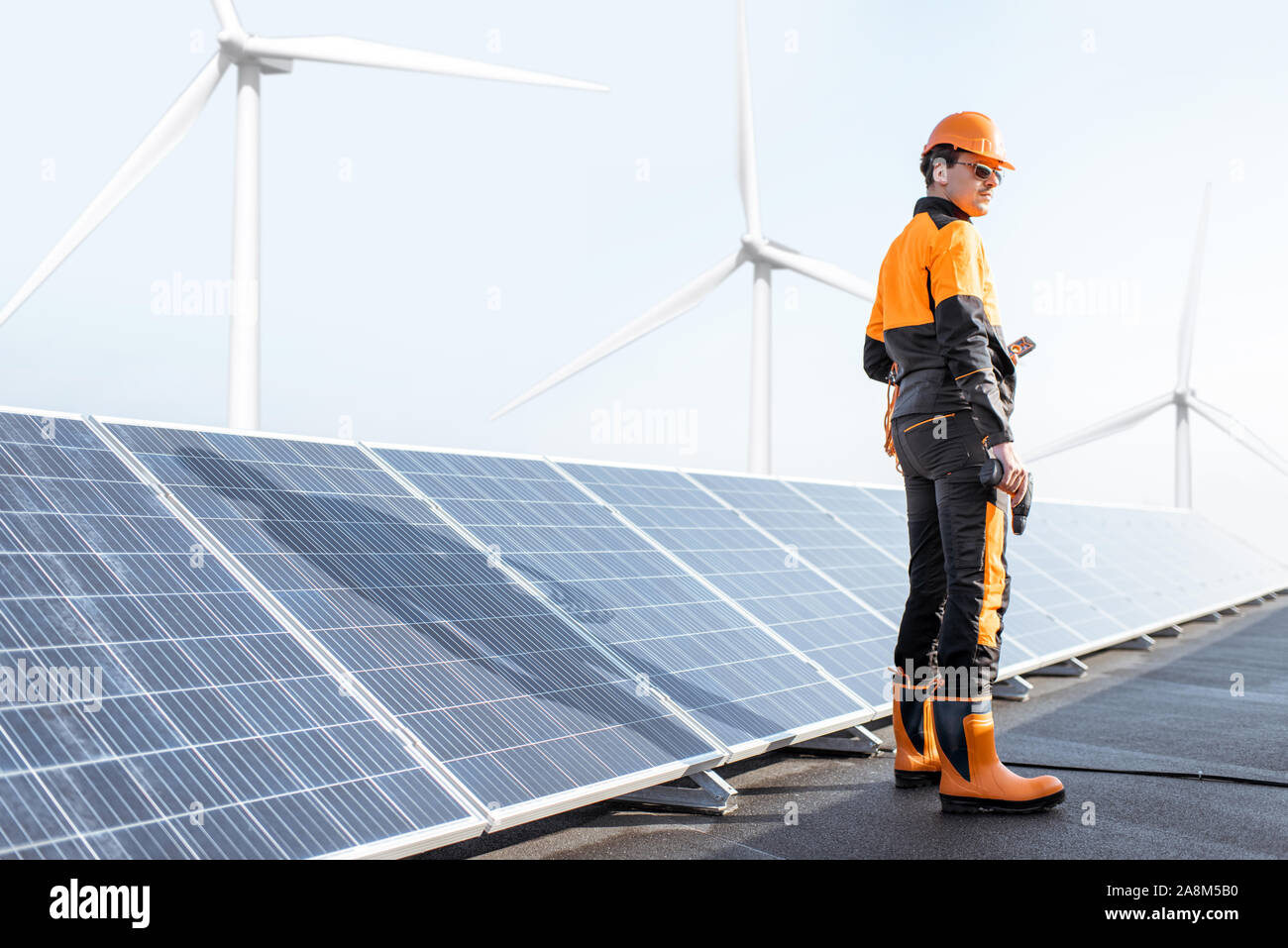 Well-equipped worker in protective orange clothing examining solar ...