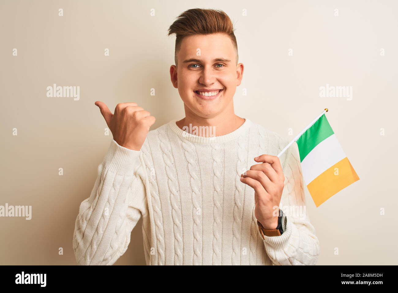 Young handsome man holding Ireland Irish flag over isolated white ...