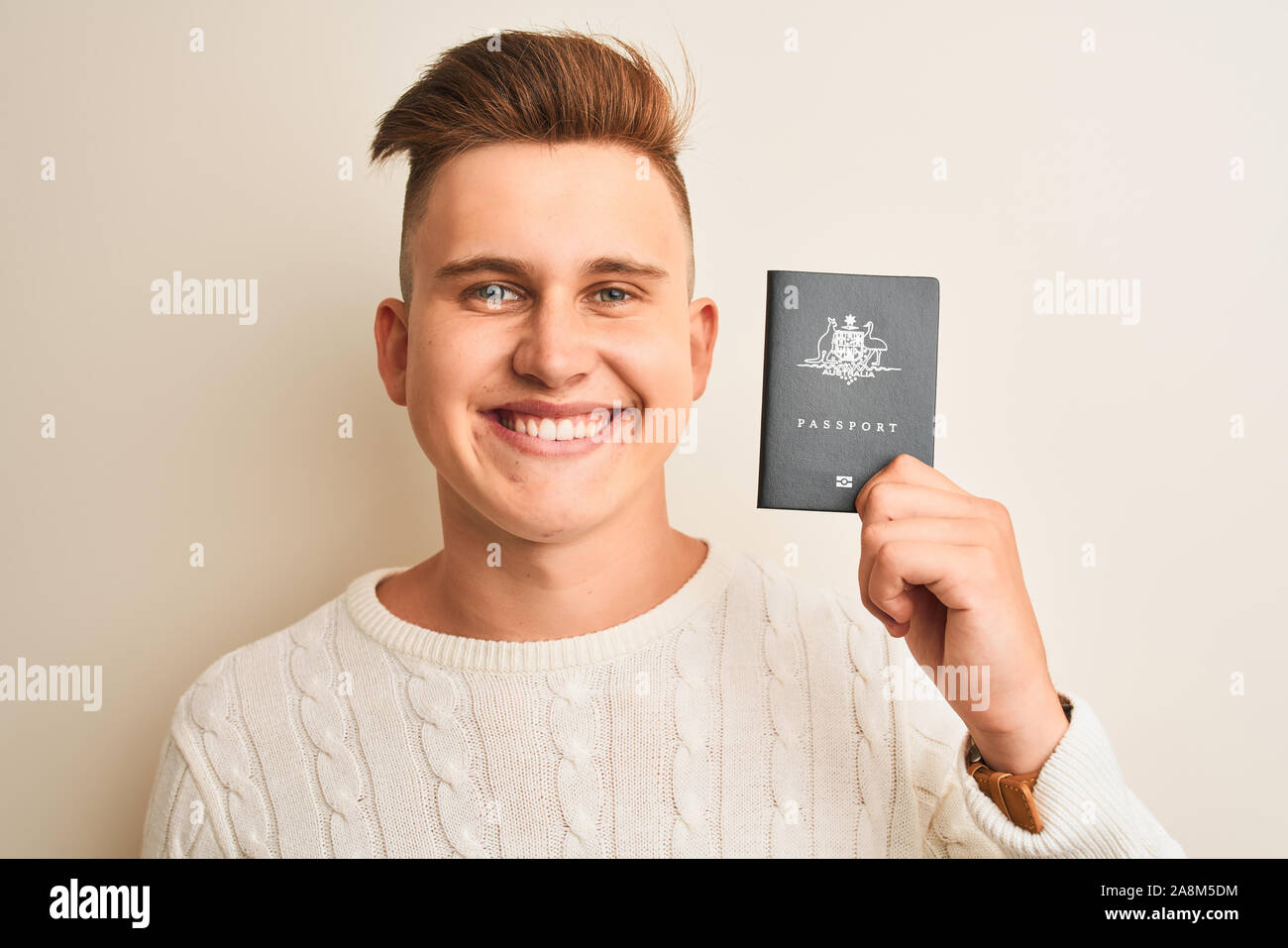 Young handsome man holding Australia Australian passport over isolated ...