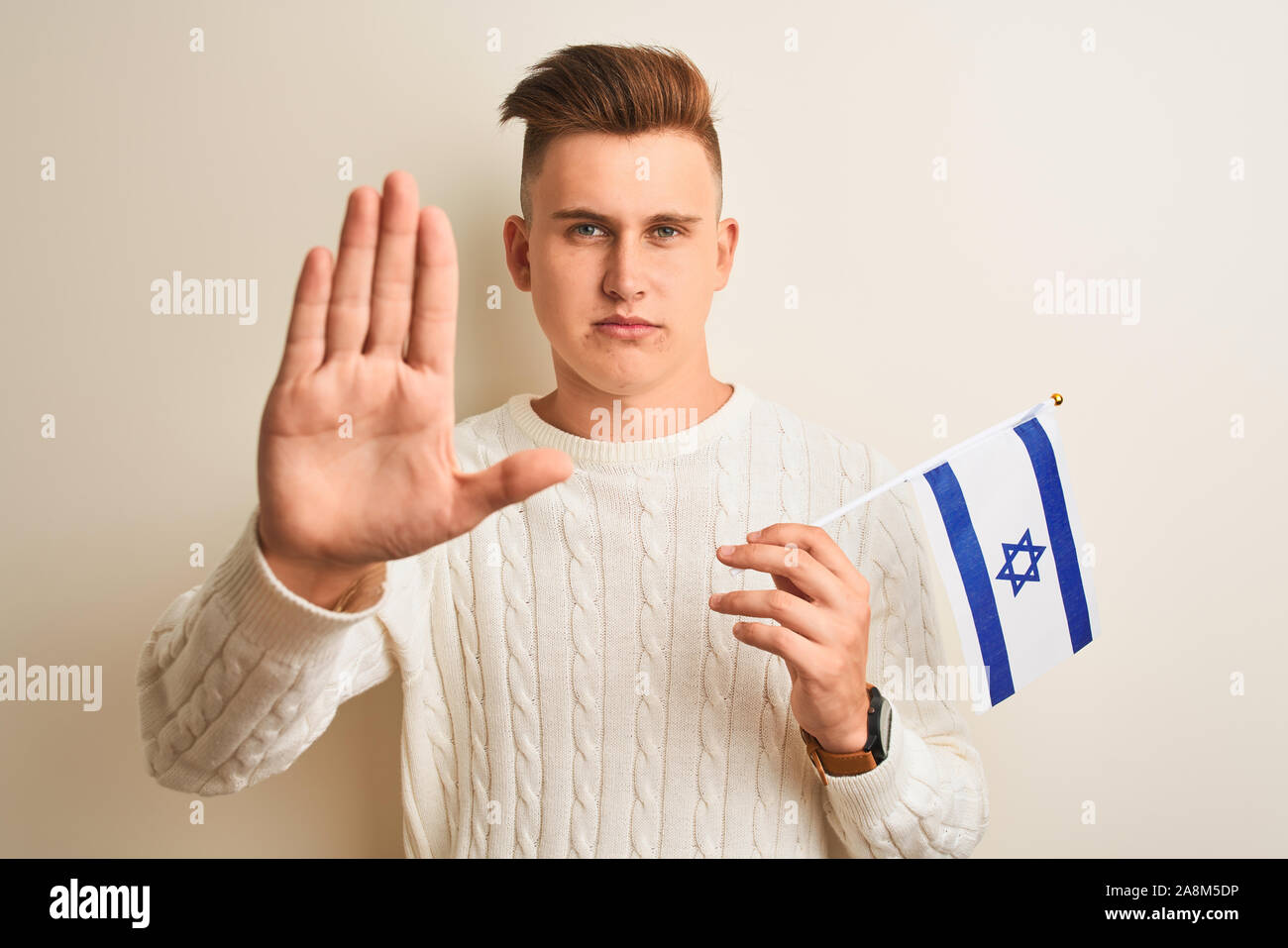 Young handsome man holding Israel Israeli flag over isolated white ...