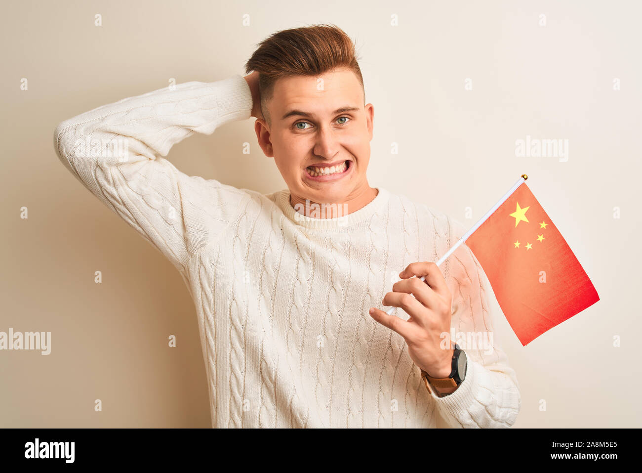 Young handsome man holding Chinese China flag over isolated white ...