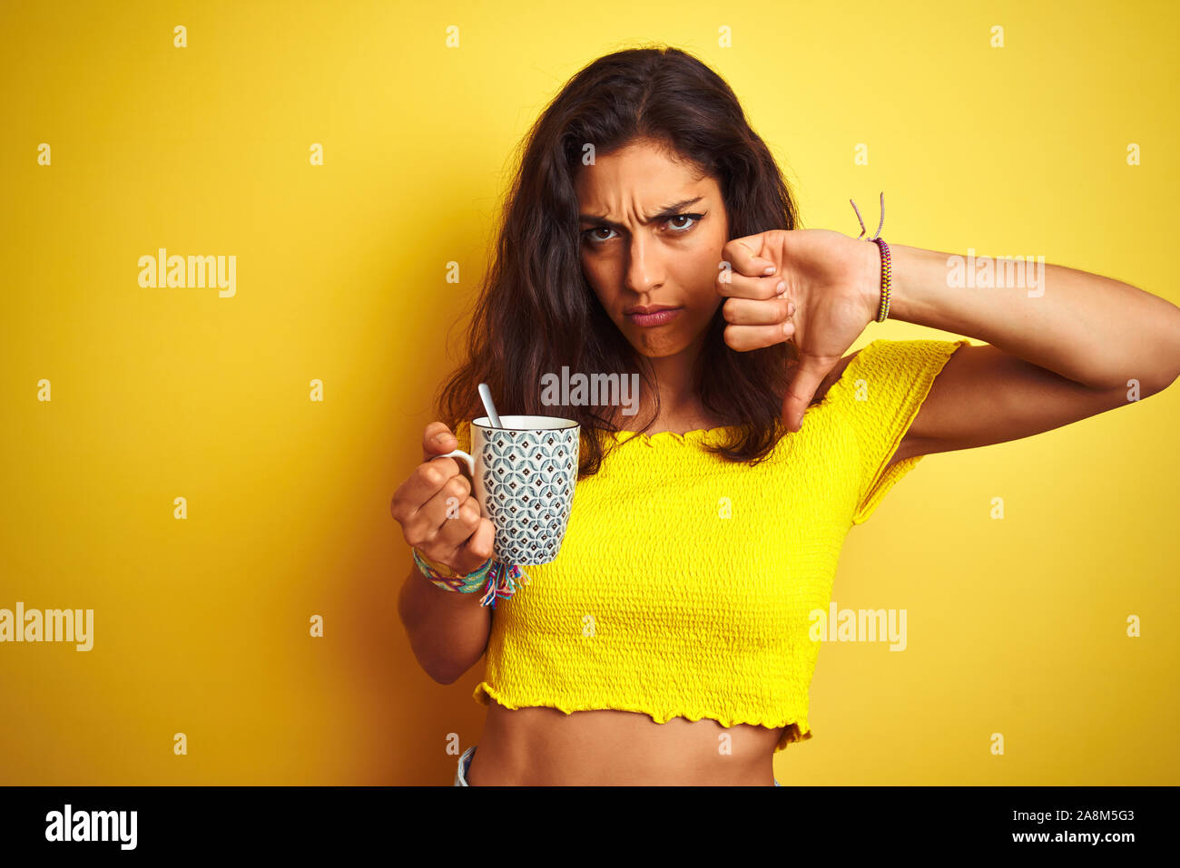 Young beautiful woman drinking cup of coffee standing over isolated ...