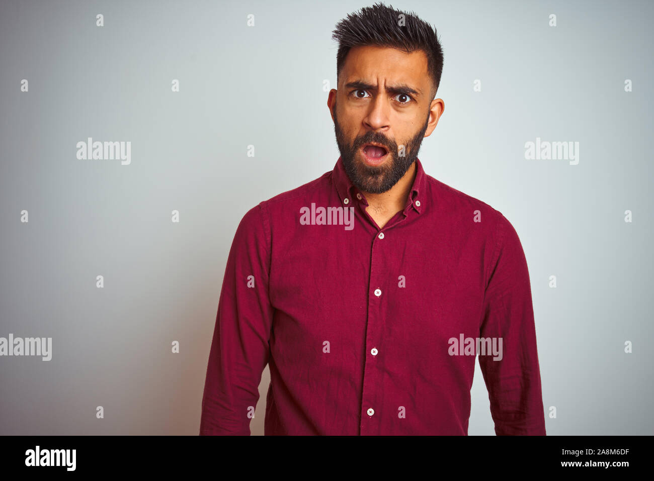Young indian man wearing red elegant shirt standing over isolated grey ...