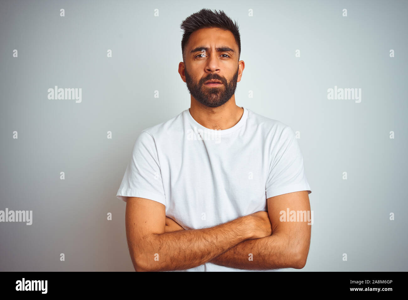 Young indian man wearing t-shirt standing over isolated white ...