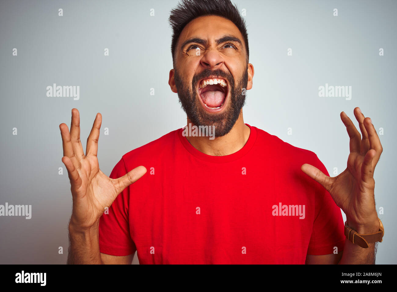 Young indian man wearing red t-shirt over isolated white background ...