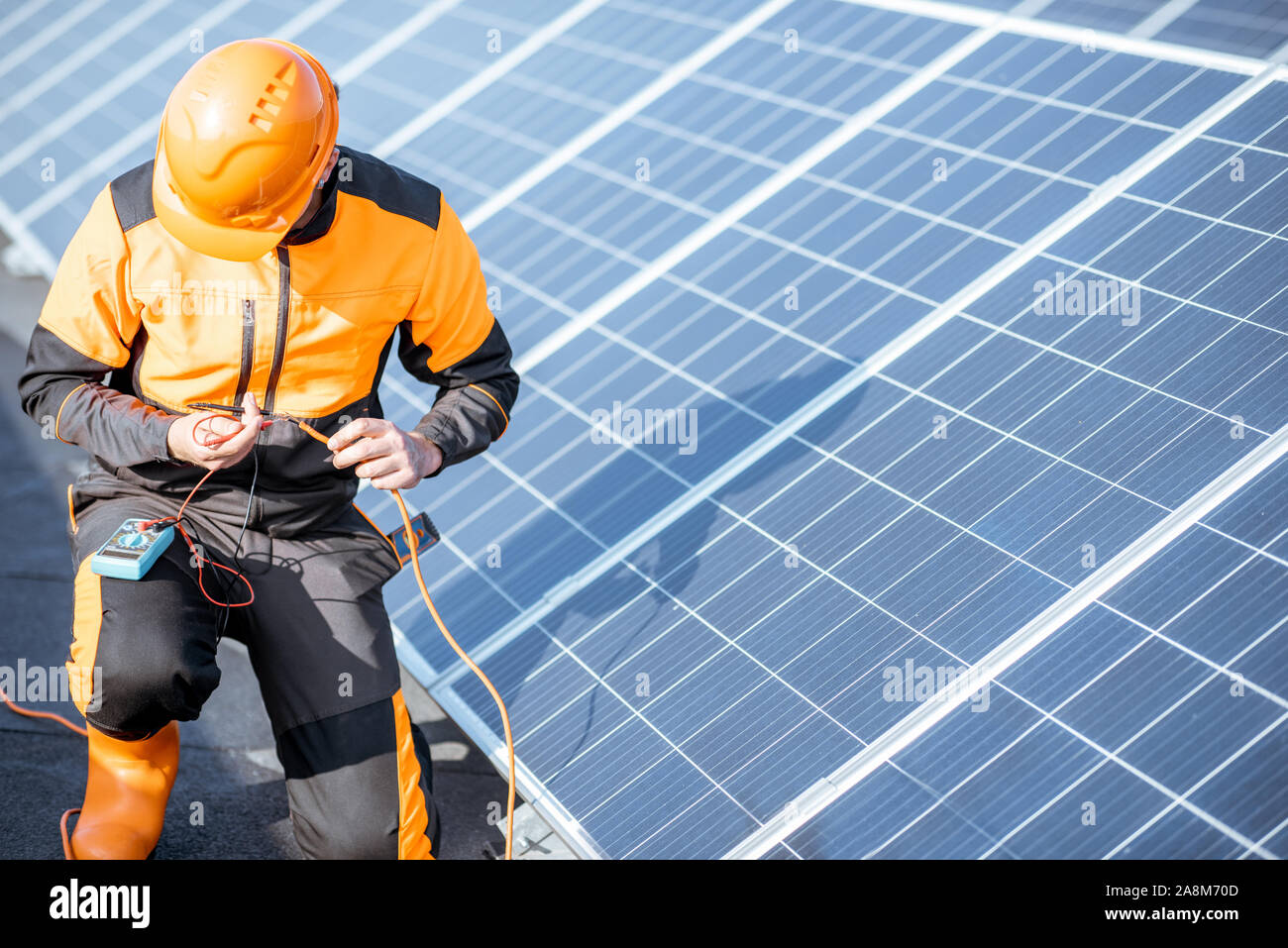 Well-equipped electrician connecting solar panels, checking the voltage ...