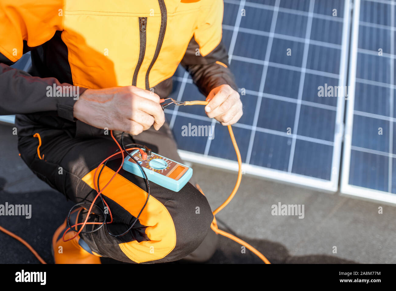Well-equipped electrician connecting solar panels, checking the voltage ...