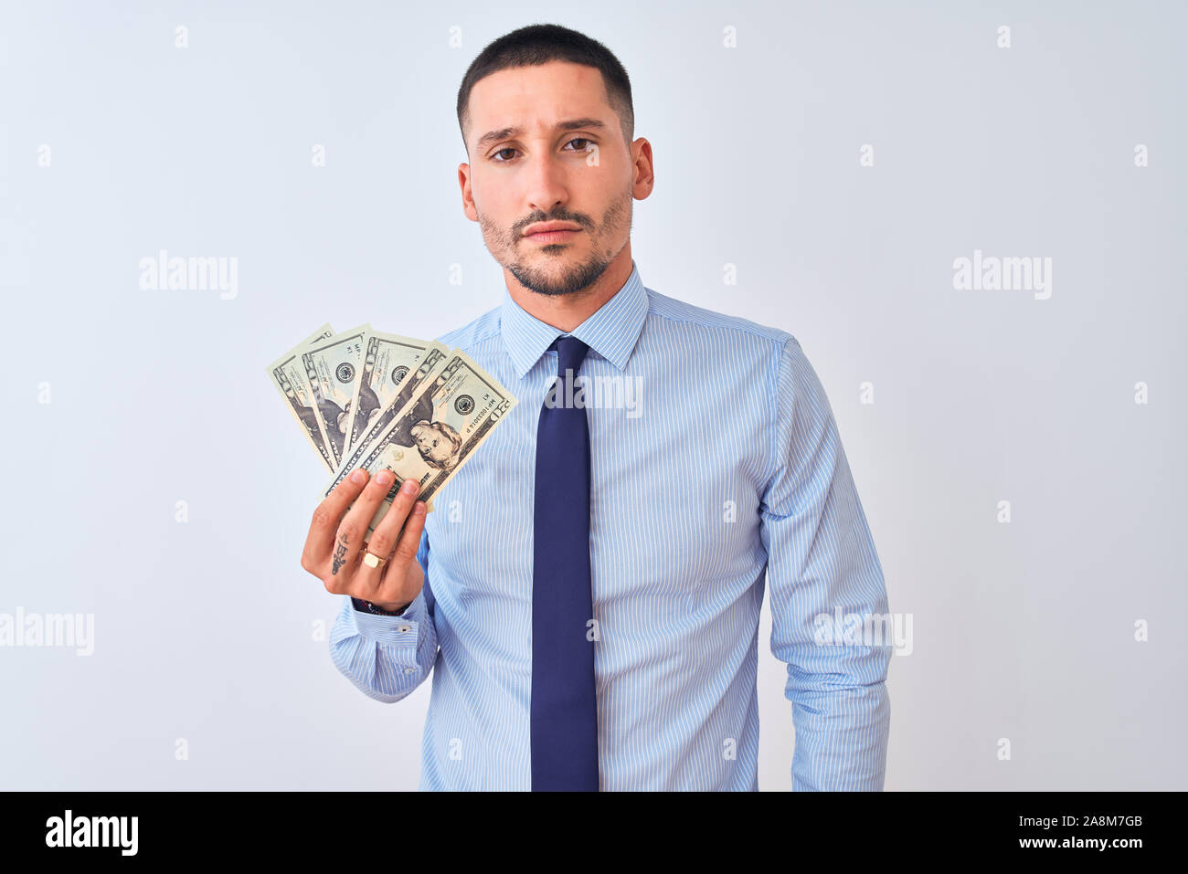 Young handsome business man holding a bunch of bank notes dollars over ...