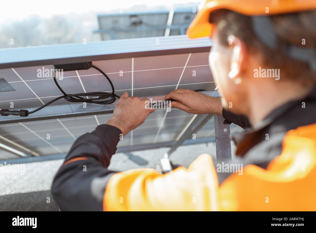 Electrician connecting wires of solar panels on a rooftop photovoltaic ...