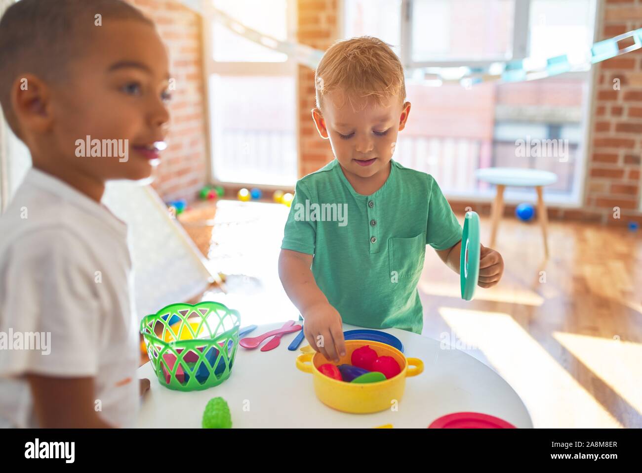Adorable toddlers playing around lots of toys at kindergarten Stock ...