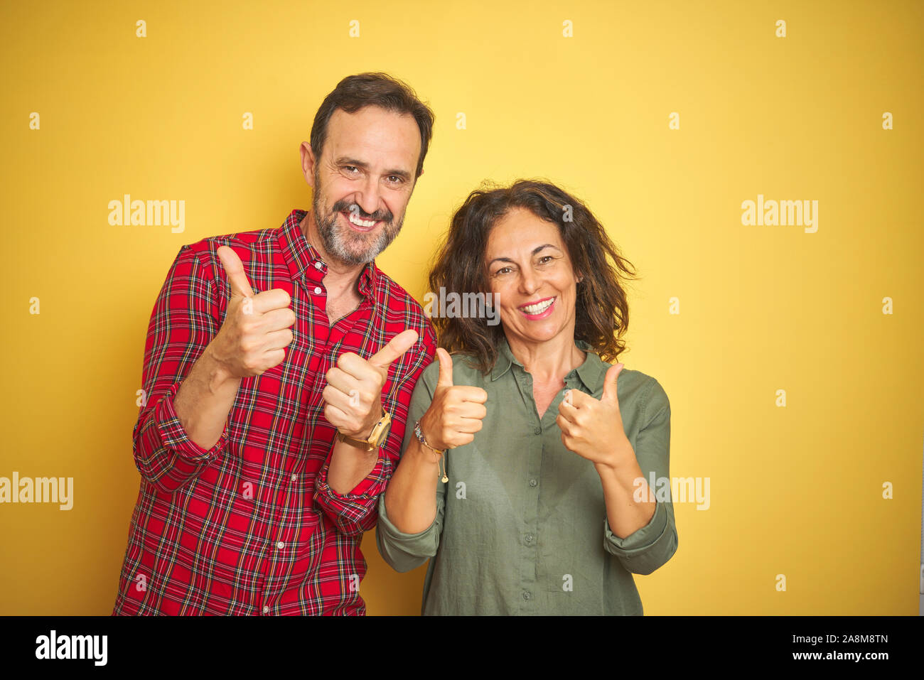 Beautiful middle age couple over isolated yellow background success ...