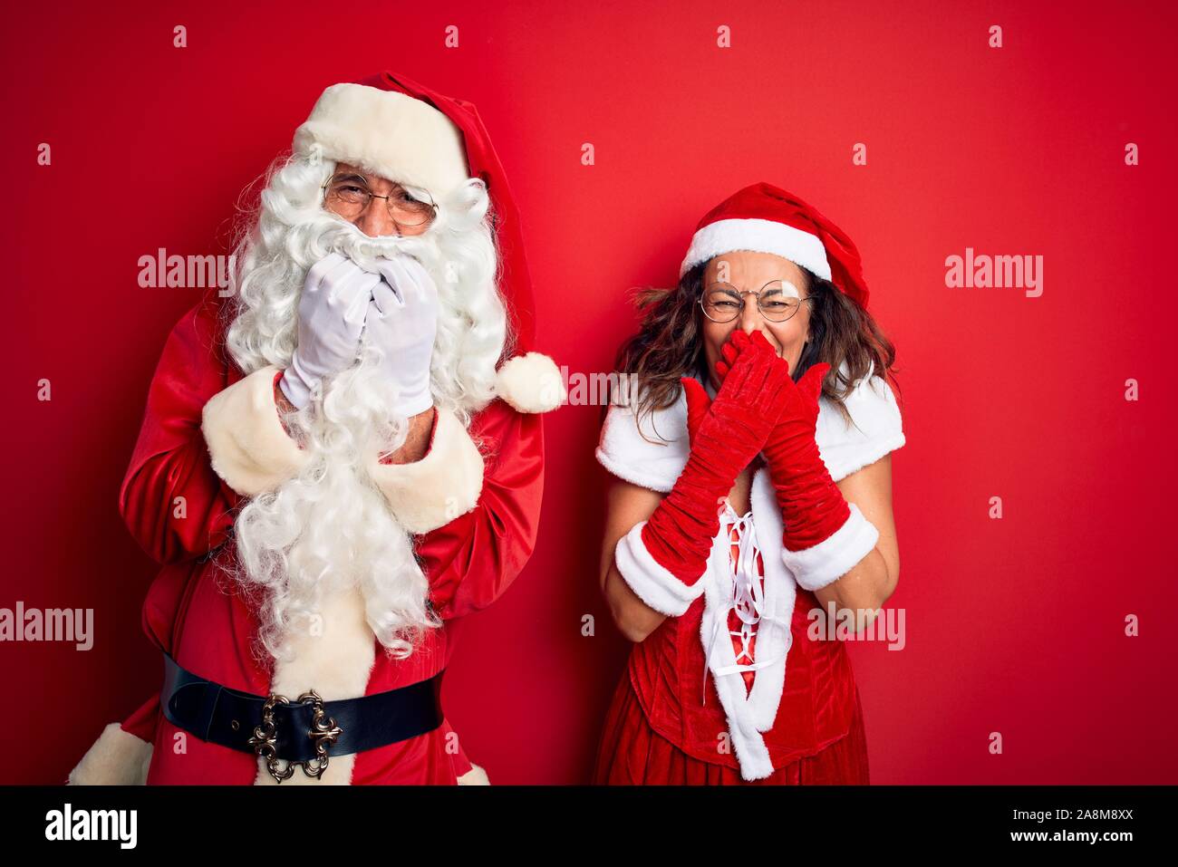 Middle age couple wearing Santa costume and glasses over isolated red ...