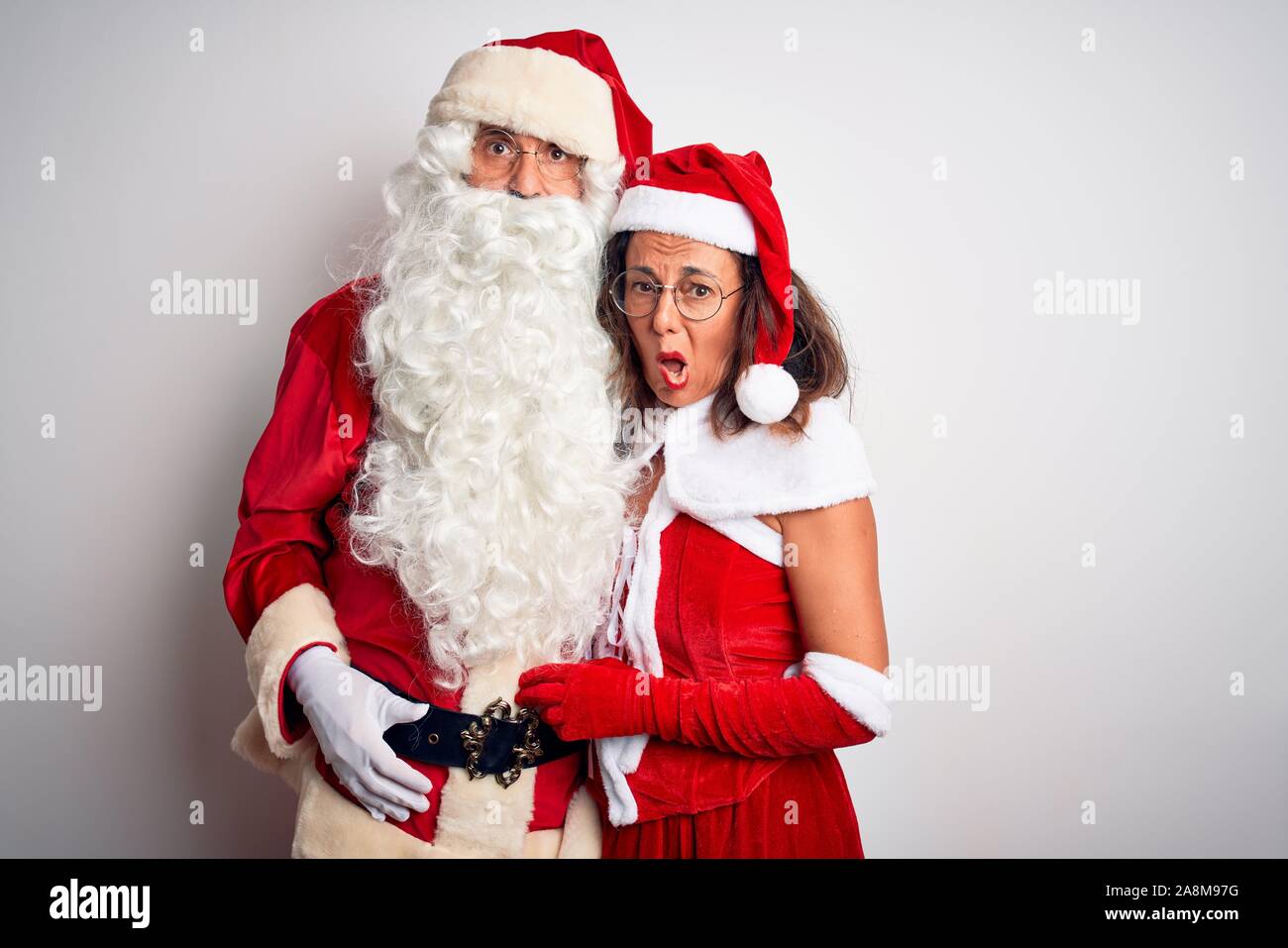 Middle age couple wearing Santa costume hugging over isolated white ...