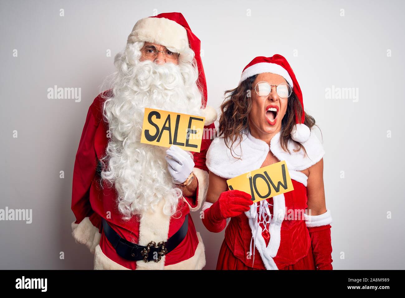 Couple wearing Santa costume holding wow and sale banner over isolated ...