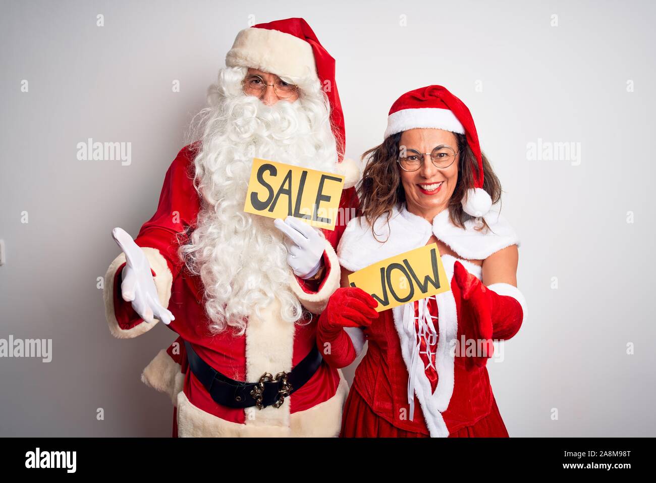 Couple wearing Santa costume holding wow and sale banner over isolated ...