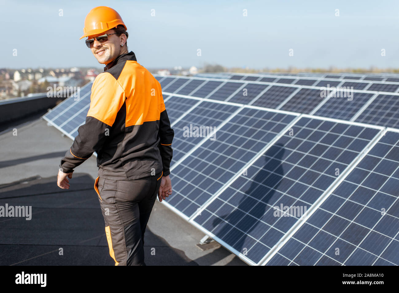 Well-equipped worker in protective orange clothing examining solar ...