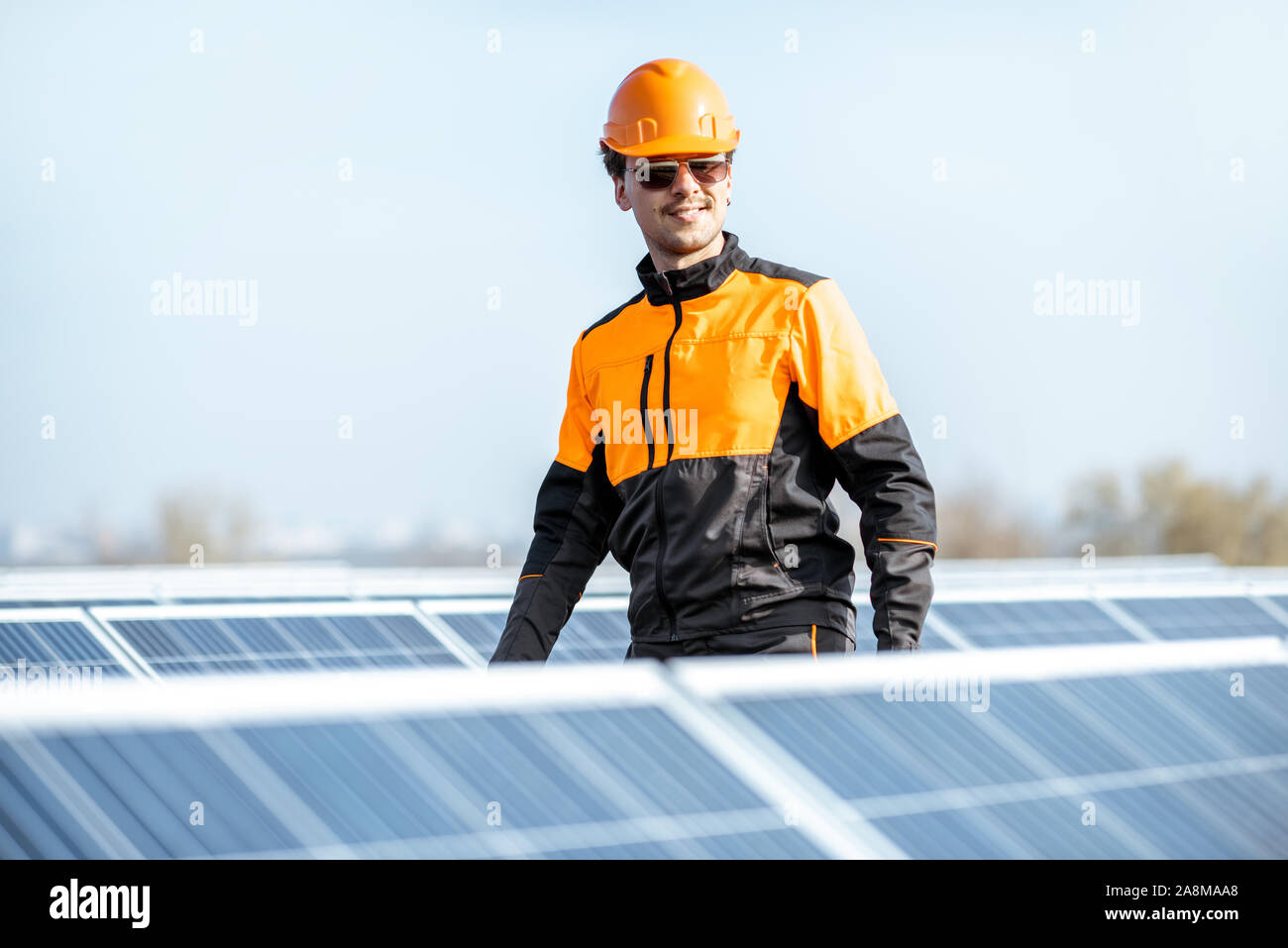 Well-equipped worker in protective orange clothing examining solar ...