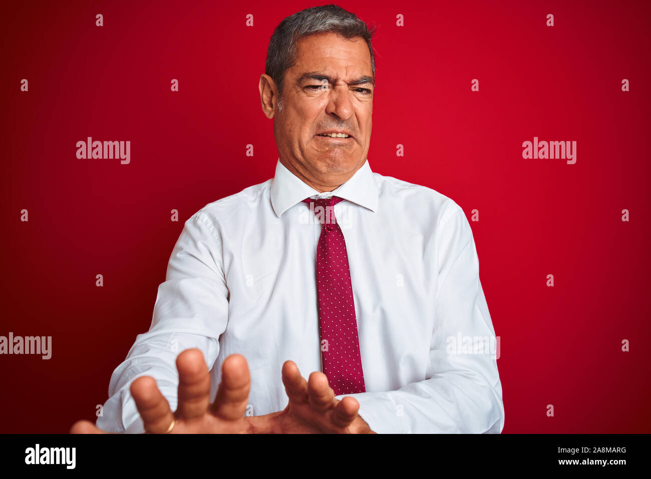 Handsome middle age businessman standing over isolated red background ...