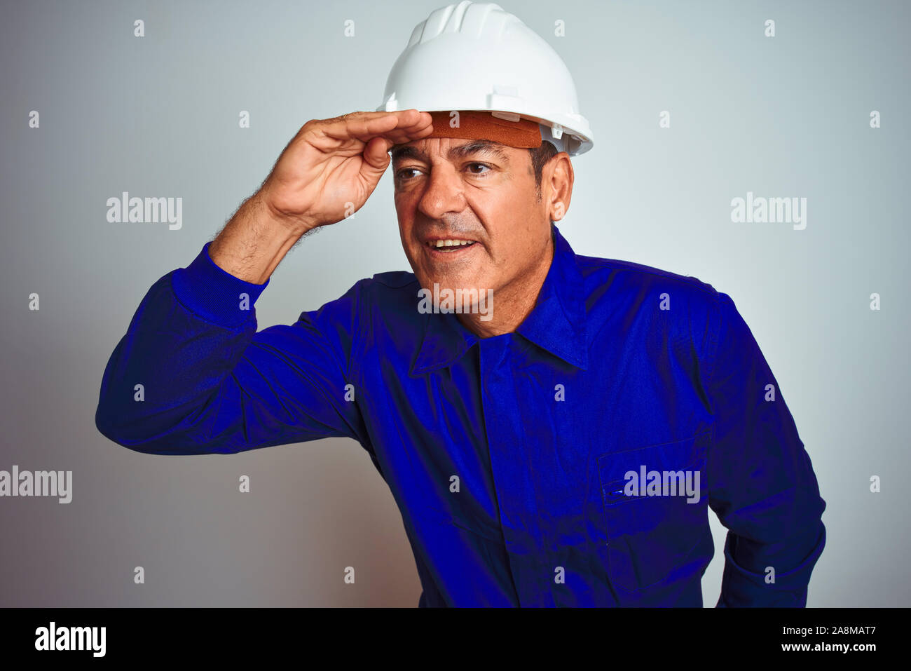 Handsome middle age worker man wearing uniform and helmet over isolated ...