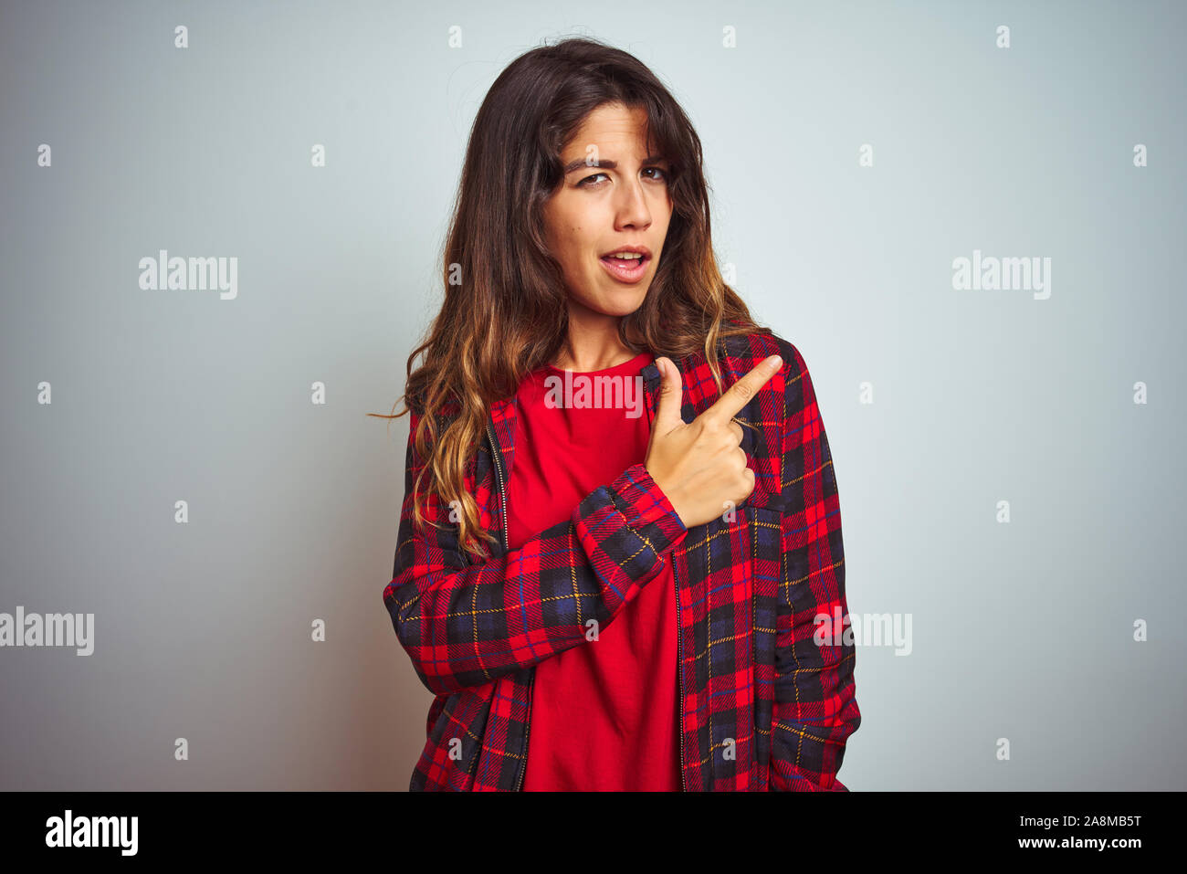 Young beautiful woman wearing red t-shirt and jacket standing over ...