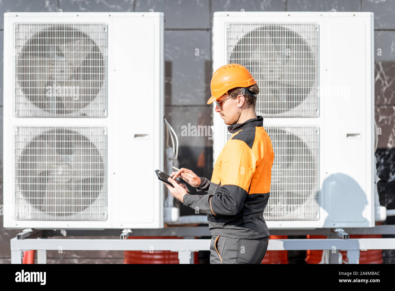 Professional workman in protective clothing adjusting the outdoor unit ...