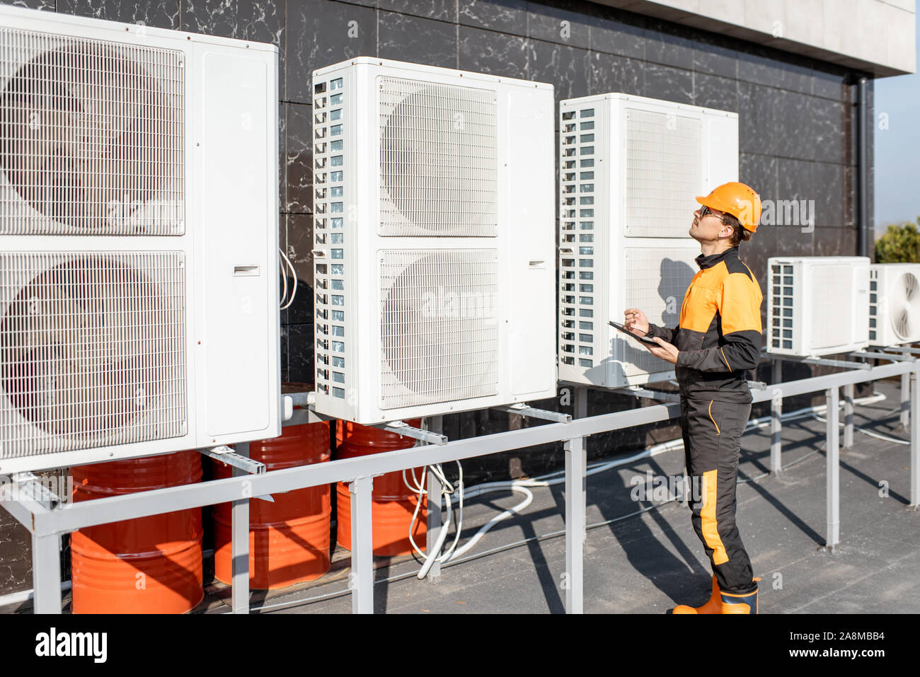 Professional workman in protective clothing adjusting the outdoor unit ...
