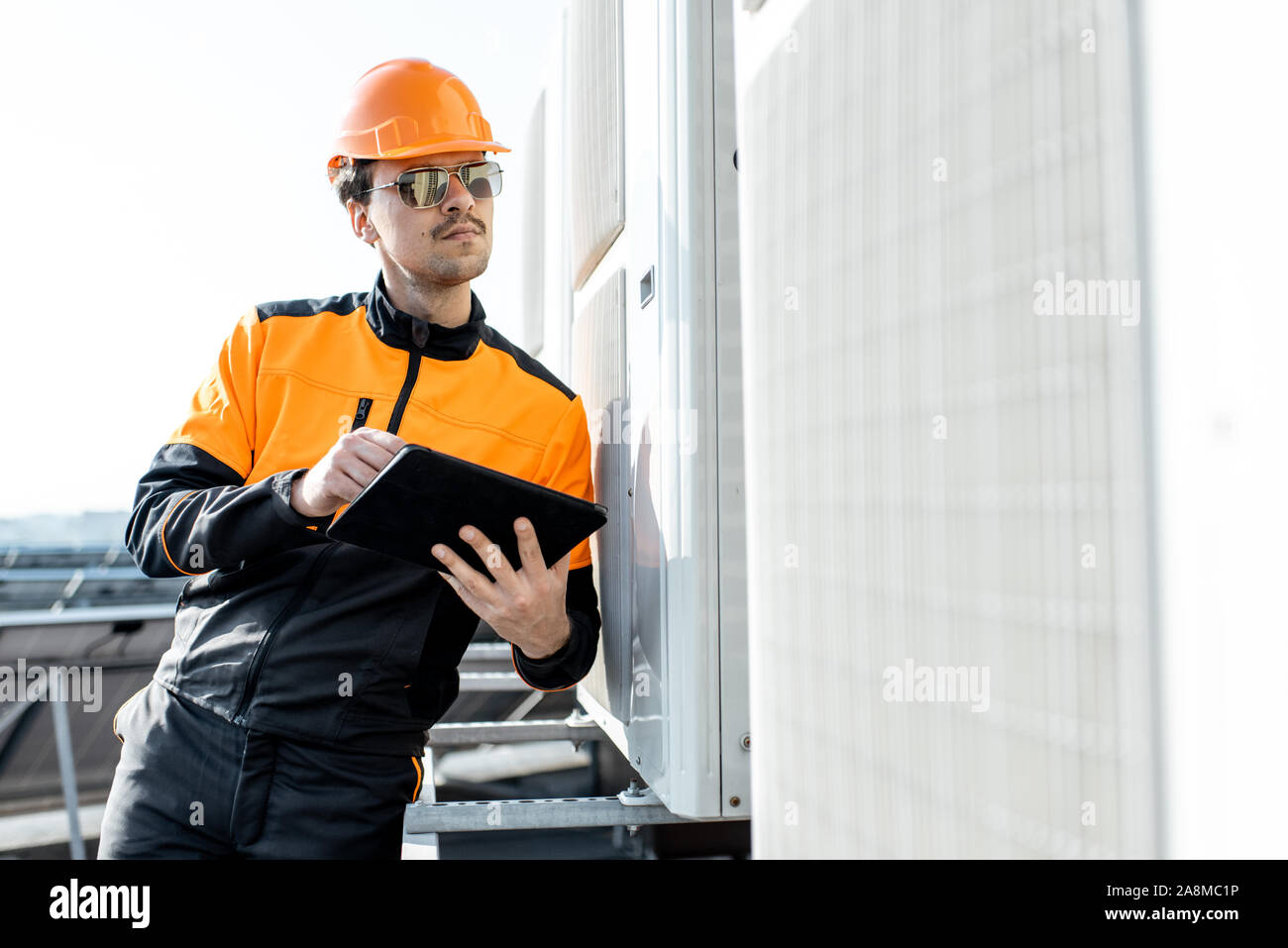 Professional workman in protective clothing adjusting the outdoor unit ...