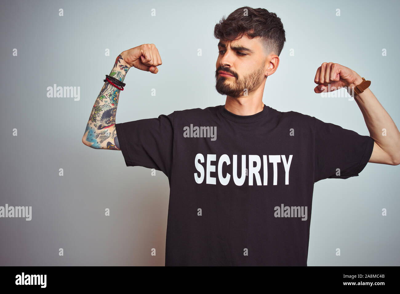 Young safeguard man with tattoo wering security uniform over isolated ...