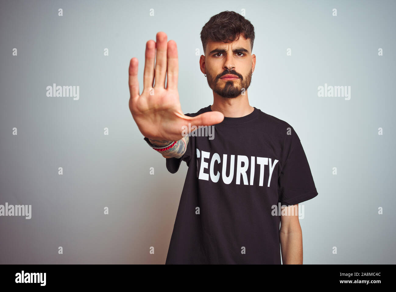 Young safeguard man with tattoo wering security uniform over isolated ...