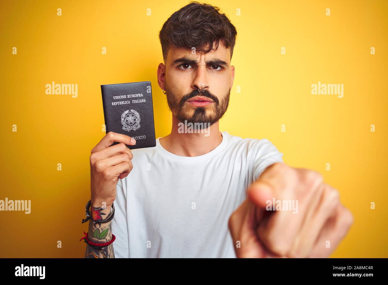 Young man with tattoo wearing Italy Italian passport over isolated ...