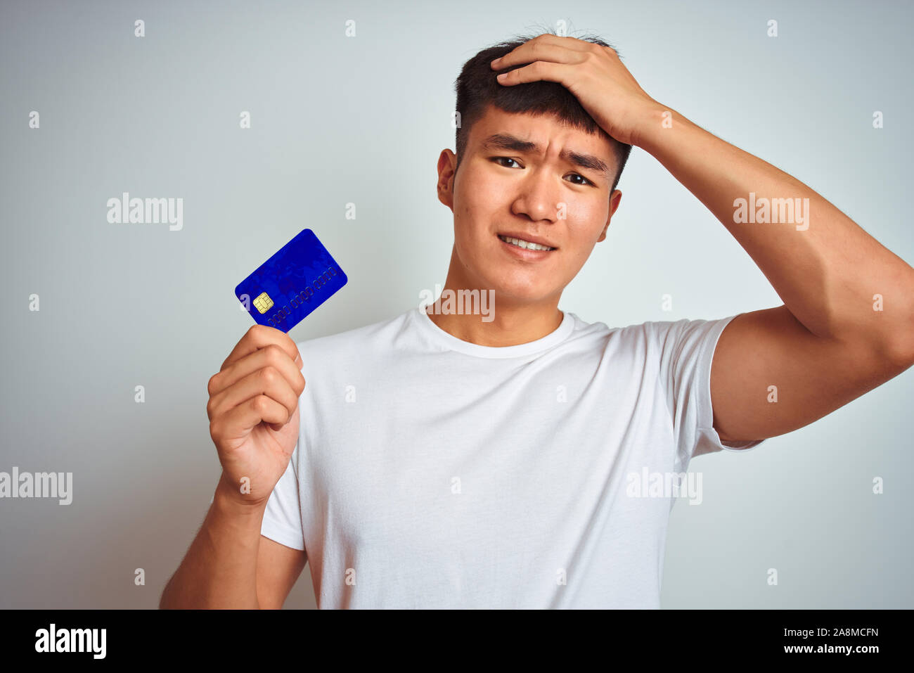 Young asian chinese man holding credit card standing over isolated ...