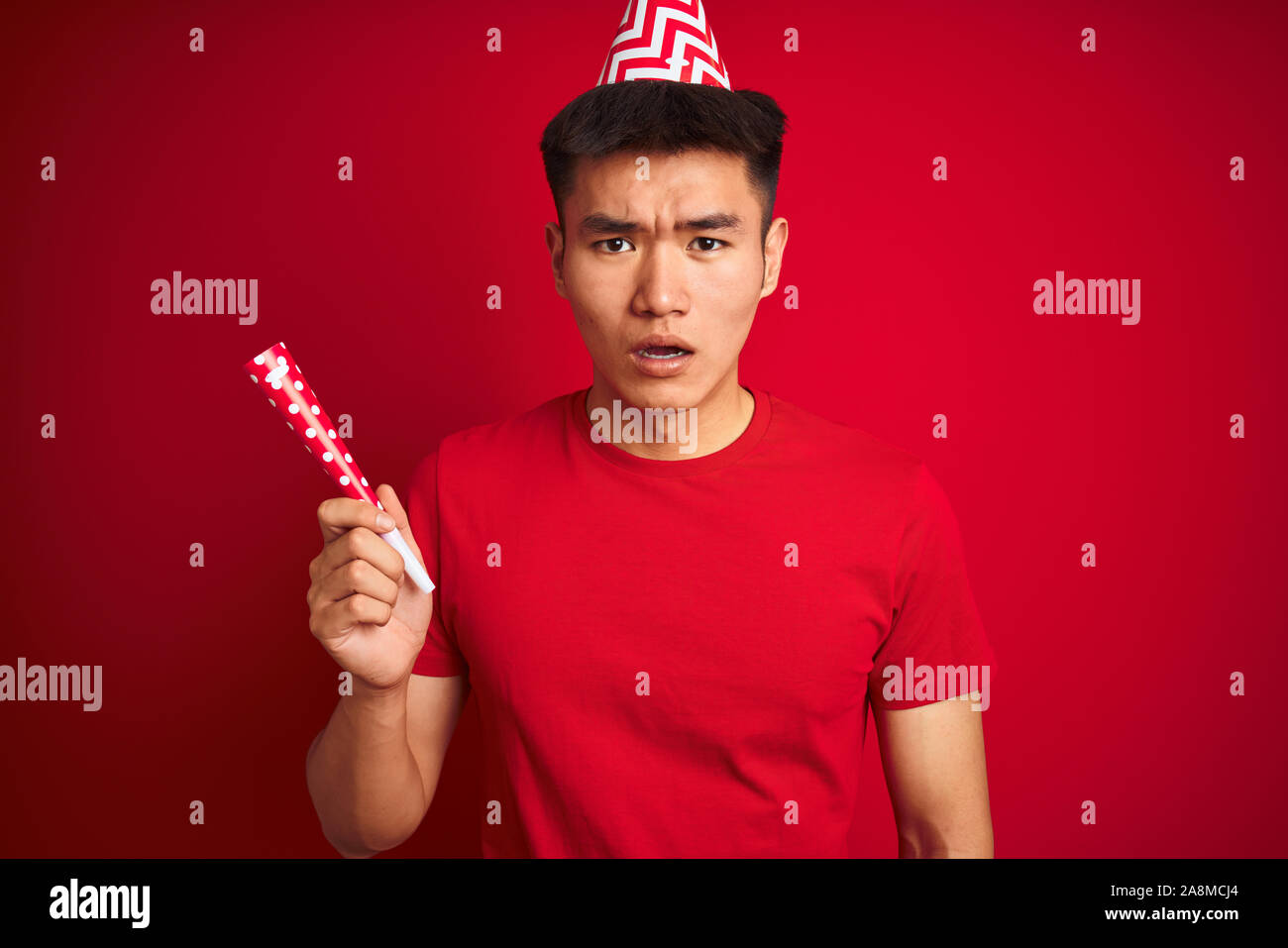 Asian chinese man on birthday celebration wearing funny hat over ...