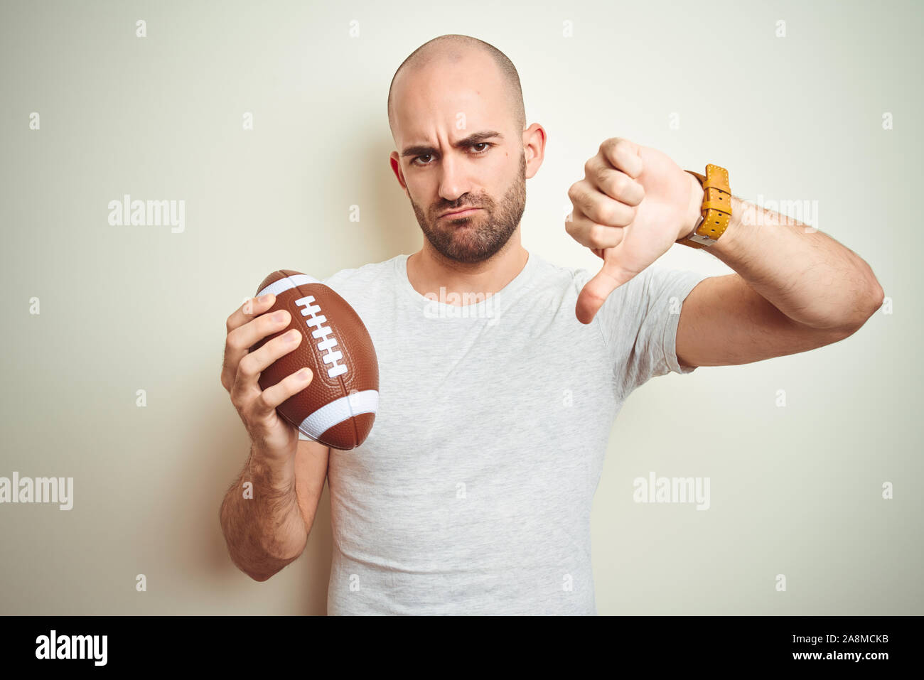 Young man holding rugby american football ball over isolated background ...