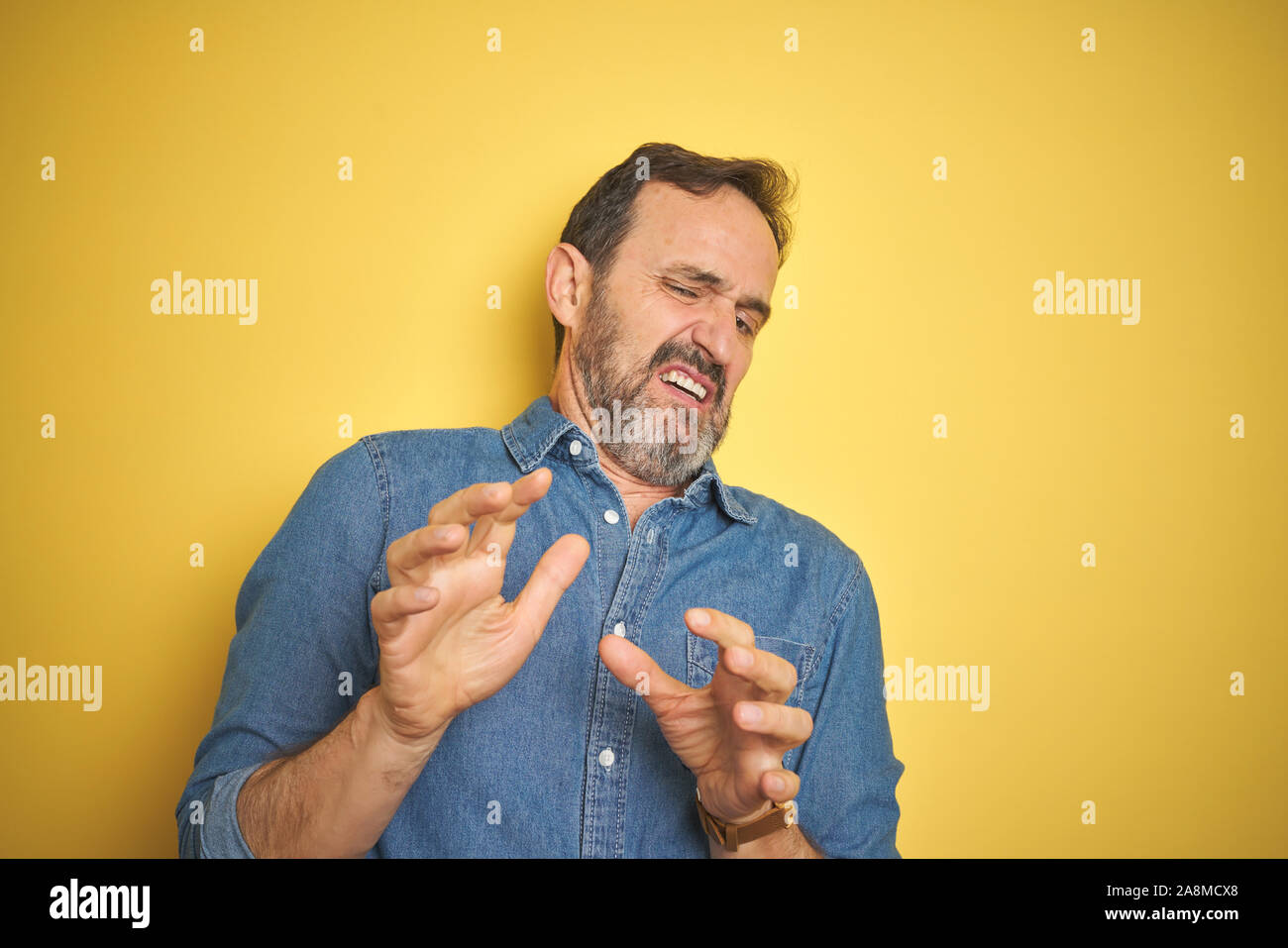 Handsome middle age senior man with grey hair over isolated yellow ...