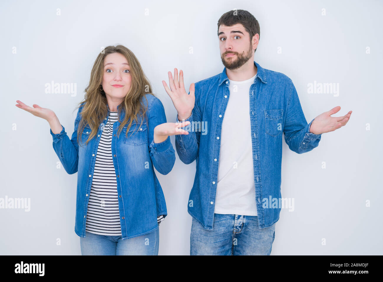 Young beautiful couple standing together over white isolated background ...