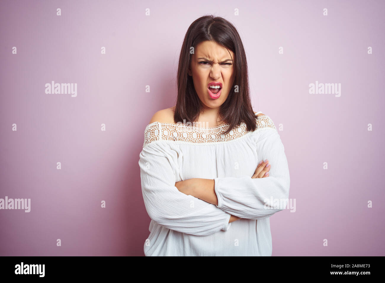 Young beautiful brunette woman over pink isolated background skeptic ...