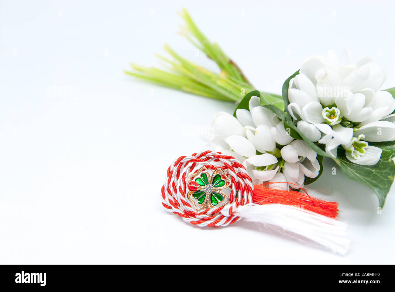 snowdrops and red and white string martisor on white with copy space ...