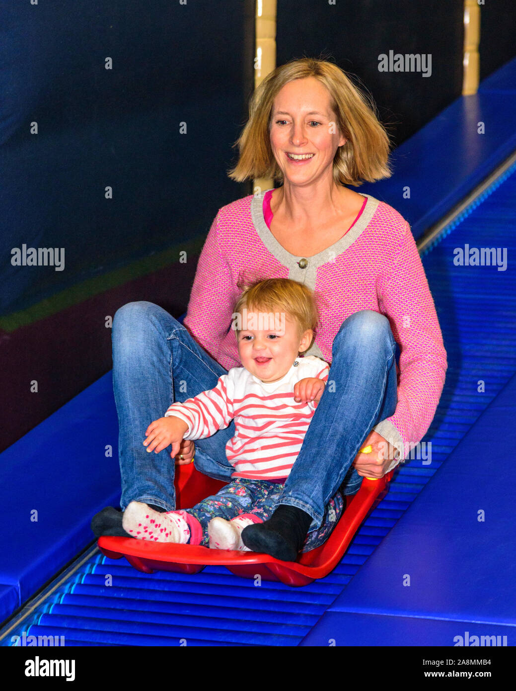Sliding fun in indoor playground Stock Photo - Alamy