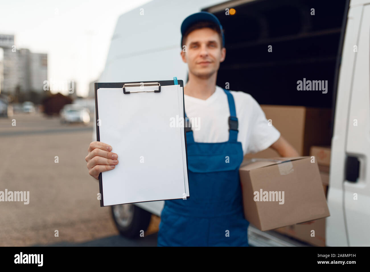 Deliveryman in uniform holding parcel, delivery Stock Photo - Alamy