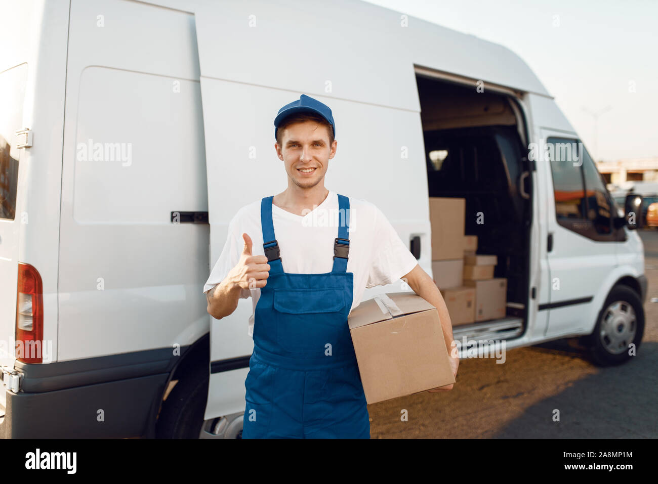 Deliveryman in uniform shows thumbs up, delivery Stock Photo - Alamy