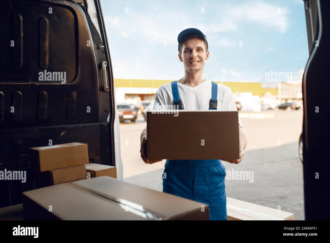 Deliveryman unloads the car with parcels, delivery Stock Photo - Alamy