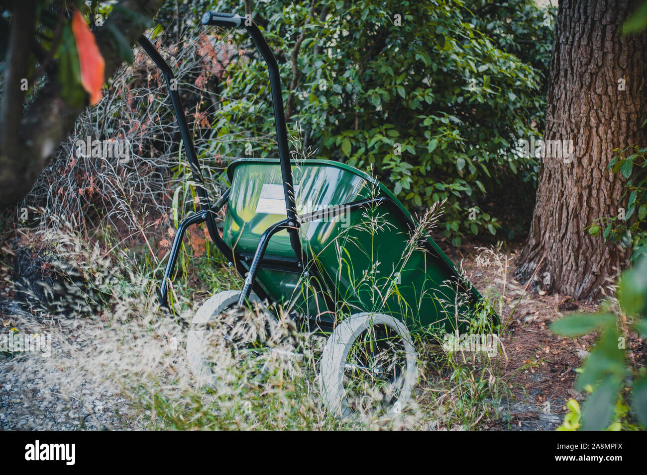 Large green garden wheelbarrow under a tree in the garden Stock Photo ...