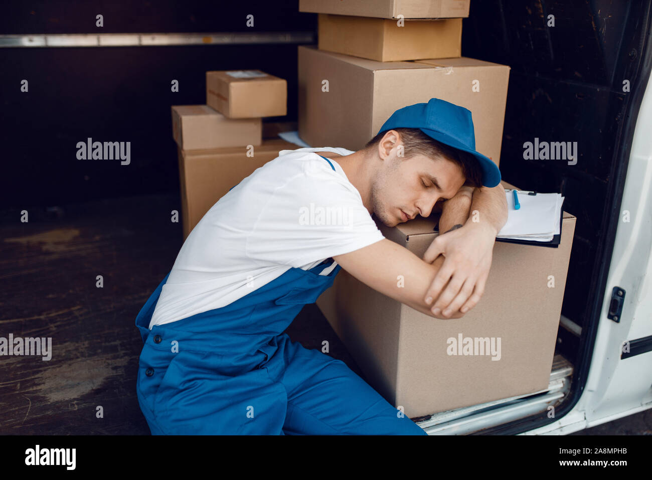 Tired loader sleeping on stack of parcels Stock Photo - Alamy