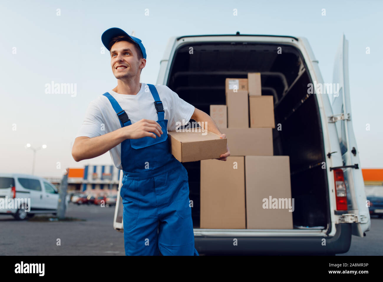 Deliveryman holds parcels at the car, delivering Stock Photo - Alamy