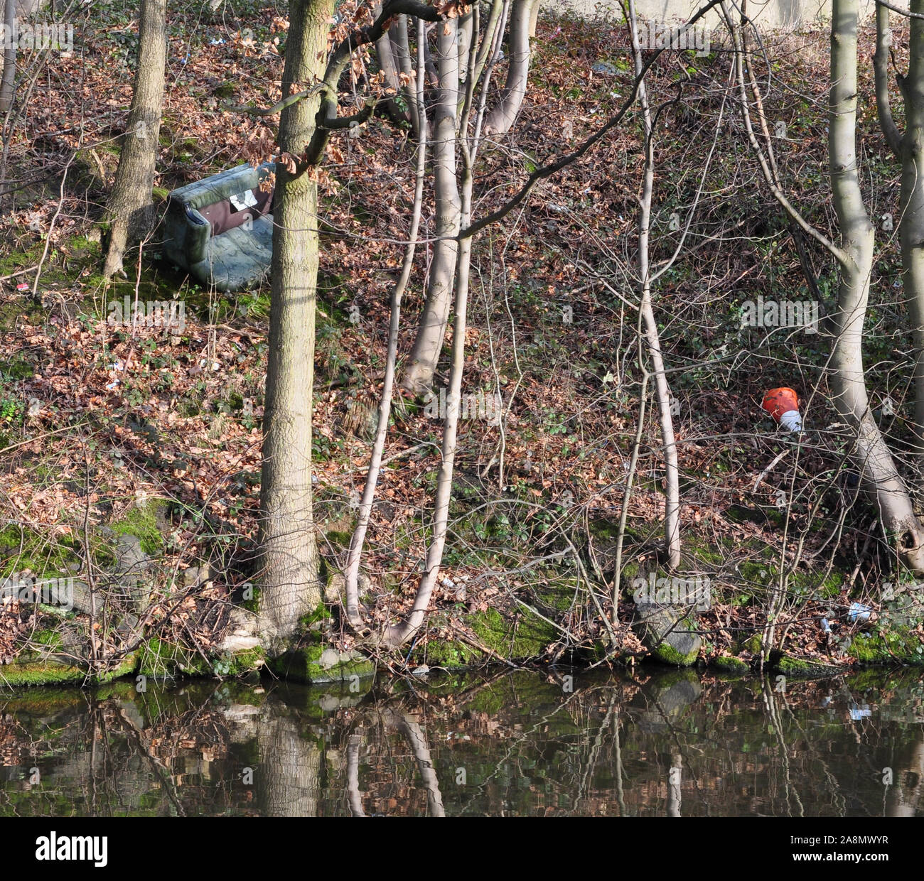 Fly tipping of sofa and cone on canal bank Stock Photo - Alamy