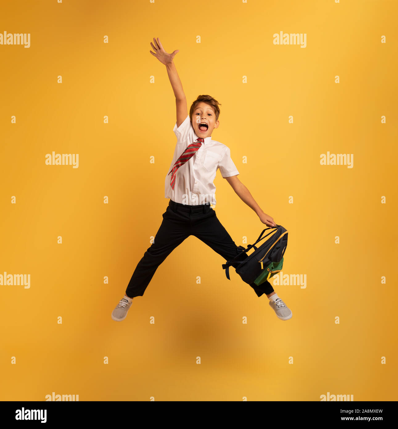 Young boy student jumps high happy for the promotion. Yellow background ...