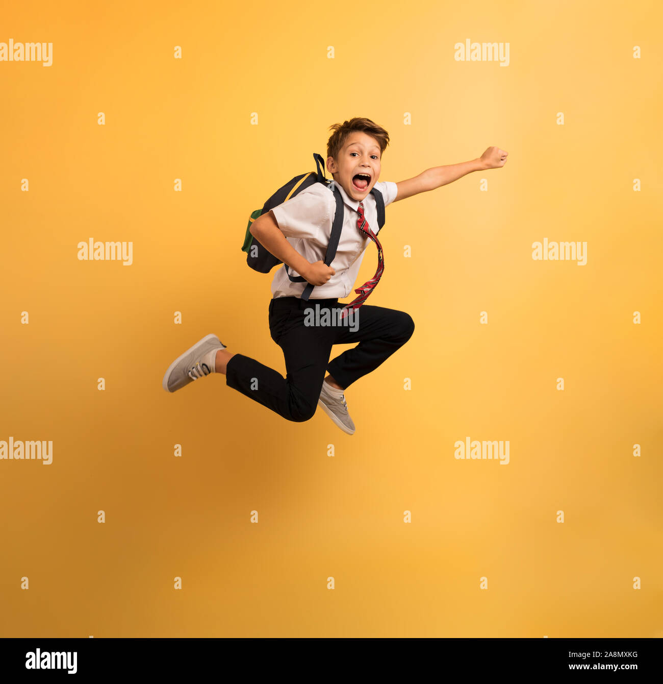 Young boy student jumps high like a super hero. Yellow background Stock ...