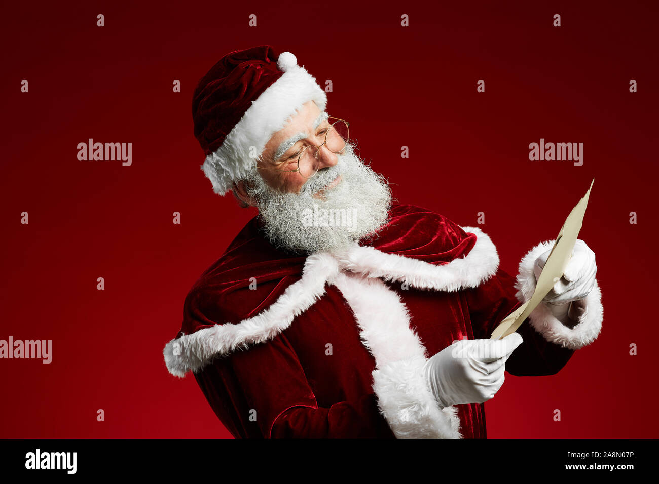 Waist up portrait of smiling Santa reading list on parchment standing ...