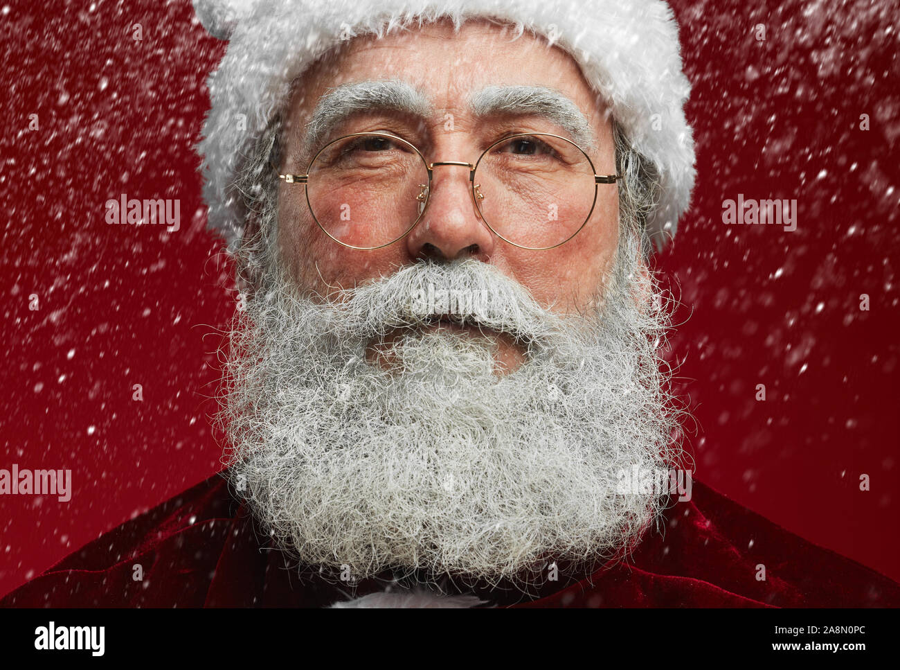 Close up portrait of classic Santa looking at camera with snow falling ...